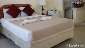 Quarto de hotel com uma cama, mesa de cabeceira, luminária, espelho e janela com um quadro.