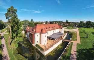 Um edifício grande e histórico com pátio, canal com água e calçada.