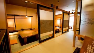Quarto japonês tradicional com tatames, portas deslizantes e uma mesa baixa com almofadas.
