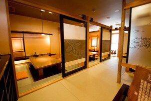 Quarto japonês tradicional com tatames, portas deslizantes e uma mesa baixa com almofadas.