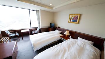 Quarto de hotel com duas camas, uma escrivaninha, uma cadeira, uma televisão e um quadro na parede.