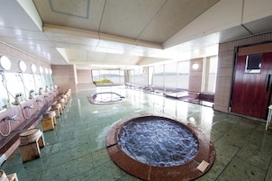 Área de banho pública com várias pias e uma banheira de hidromassagem central.