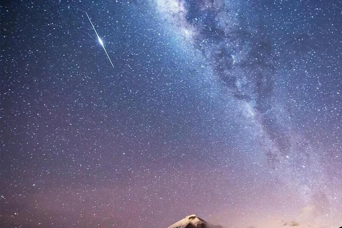 Céu noturno com estrelas e a Via Láctea, uma montanha ao fundo, e o logotipo do 'Hacienda Los Mortinos Hotel-restaurant'.
