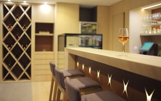 Uma área de bar moderna com adega, banquetas e um copo de vinho.