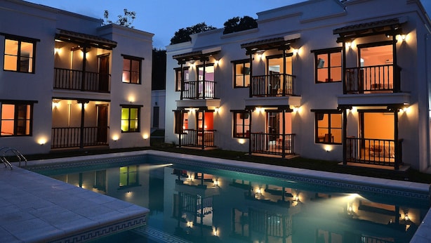 Vista da piscina de um hotel, com várias varandas e iluminação externa.