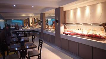 Um restaurante moderno com área de buffet, diversas mesas e cadeiras.