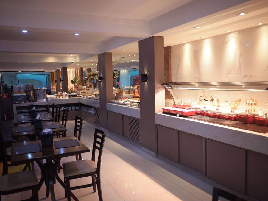 Um restaurante moderno com área de buffet, diversas mesas e cadeiras.