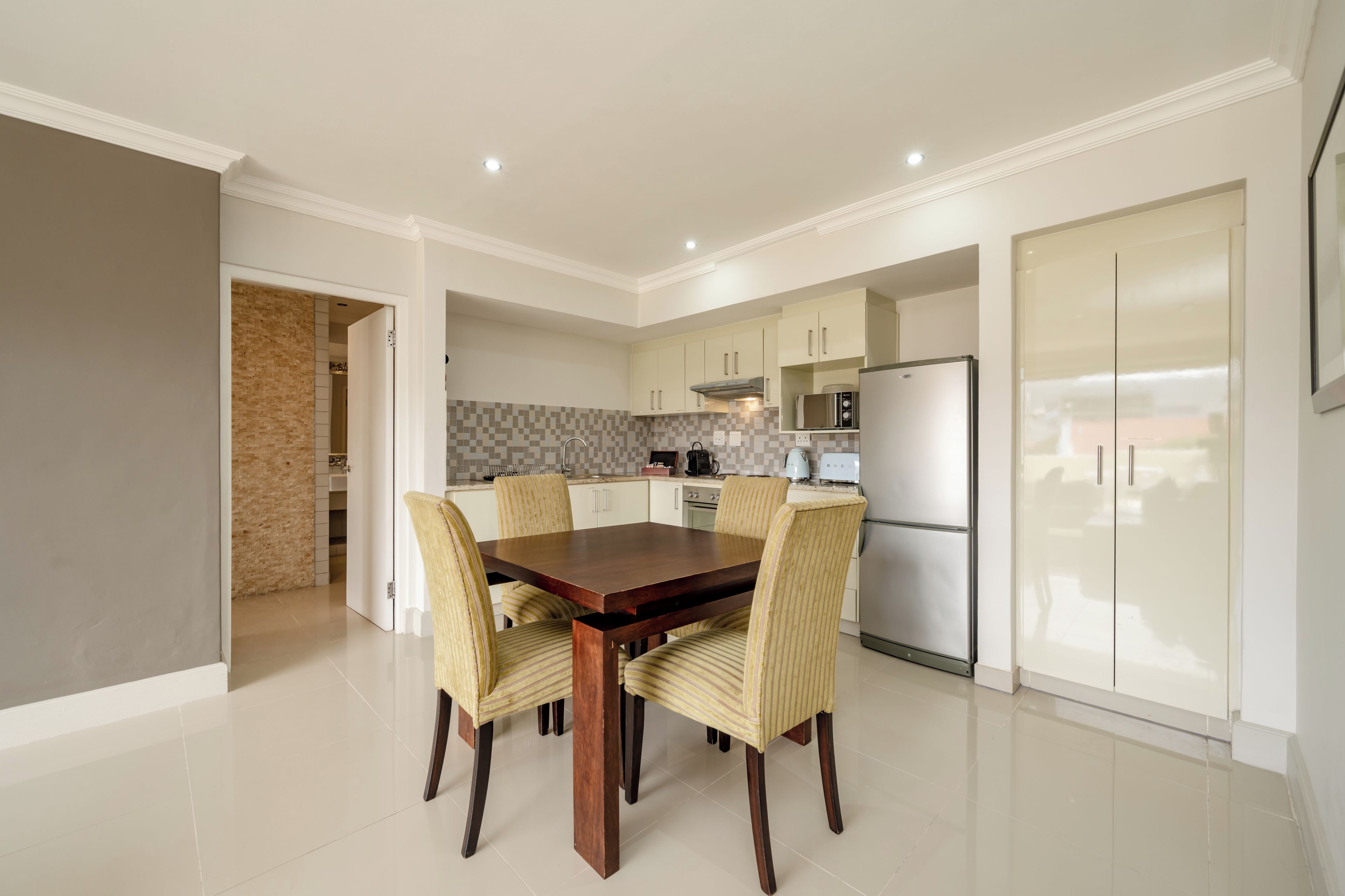 Cozinha moderna com mesa e cadeiras, geladeira e micro-ondas.