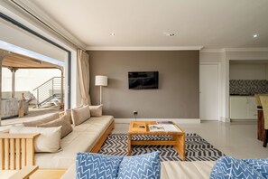 Uma sala de estar moderna com sofá, mesa de centro e vista para a varanda externa.