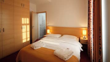 Quarto de hotel com cama, mesas de cabeceira, guarda-roupa e janela com vista.