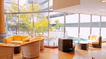Um espaço interno amplo, com móveis de vime, janelas grandes e vista para o verde lá fora.