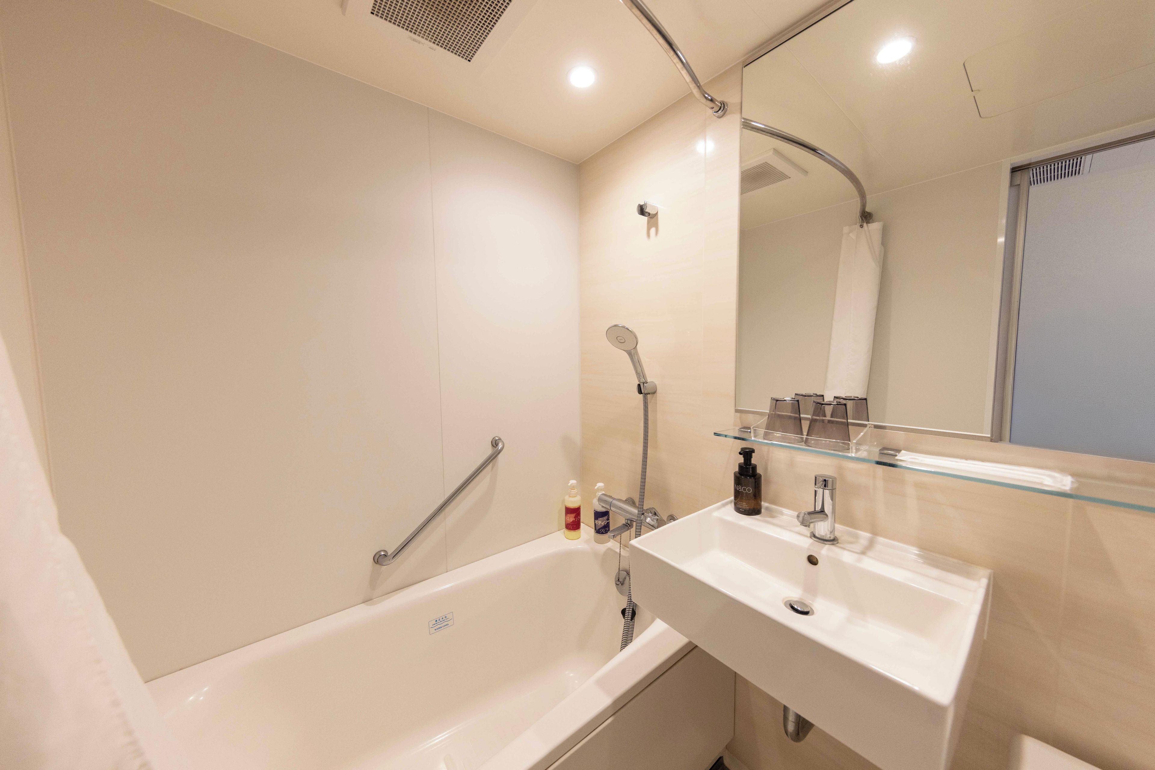 Uma casa de banho moderna com banheira, lavatório e prateleira de vidro com produtos de higiene pessoal.