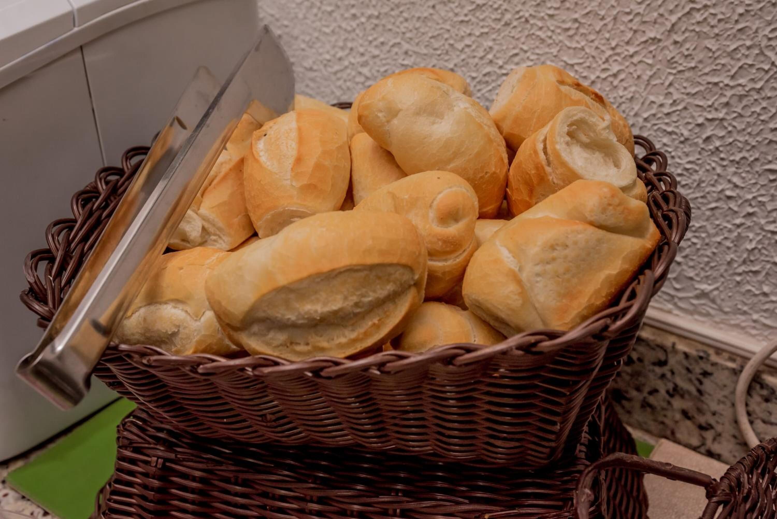 Uma cesta de vime cheia de pães dourados.