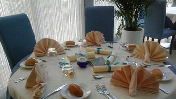 Mesa de jantar posta com guardanapos dobrados, pratos, talheres e um copo de água.