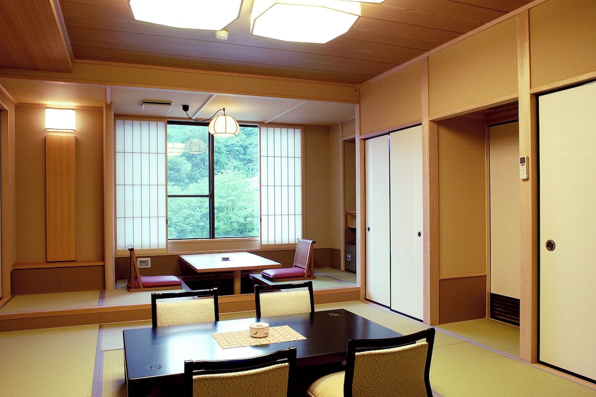 Um quarto japonês tradicional, com chão de tatame, uma mesa baixa e portas deslizantes.