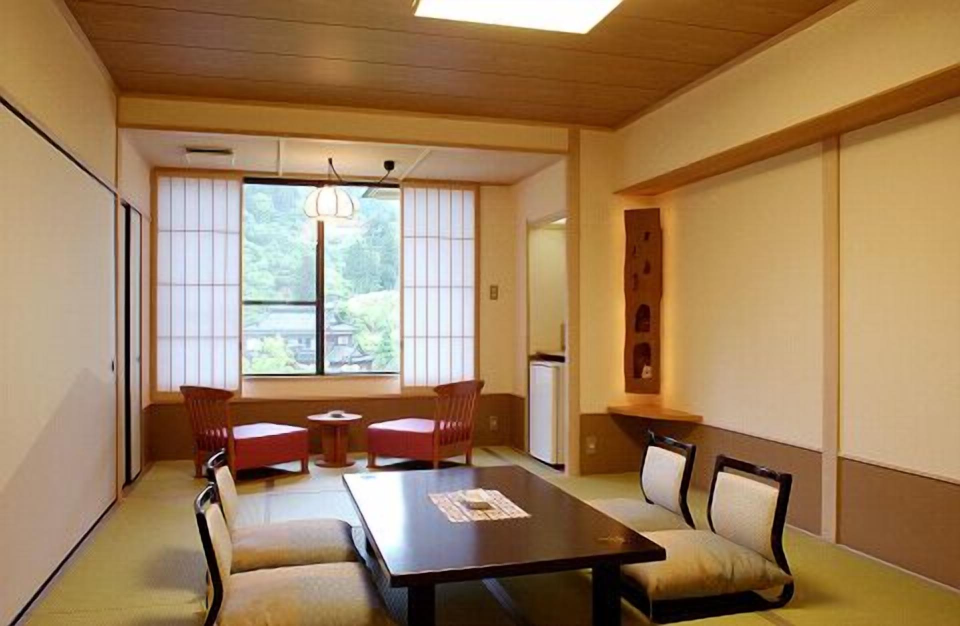 Um quarto japonês tradicional com piso de tatame, uma mesa baixa e vista para um jardim através de biombos shoji.