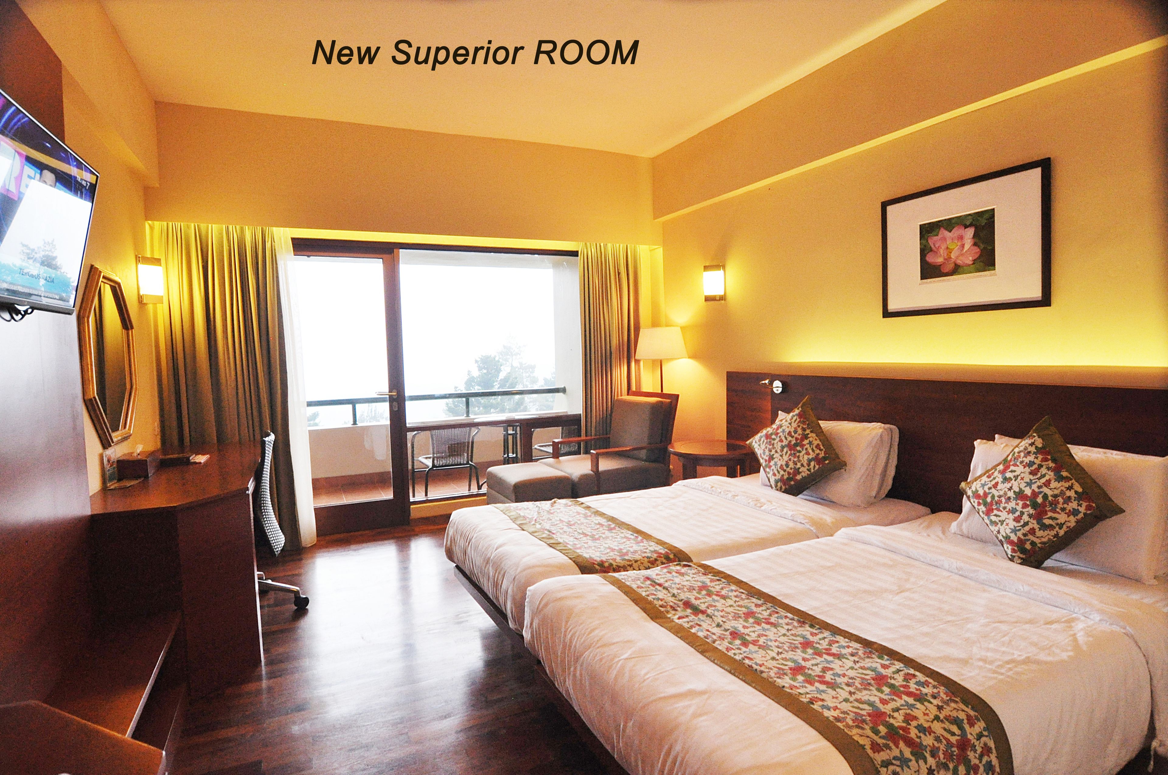 Quarto de hotel com duas camas, uma escrivaninha, televisão e varanda.