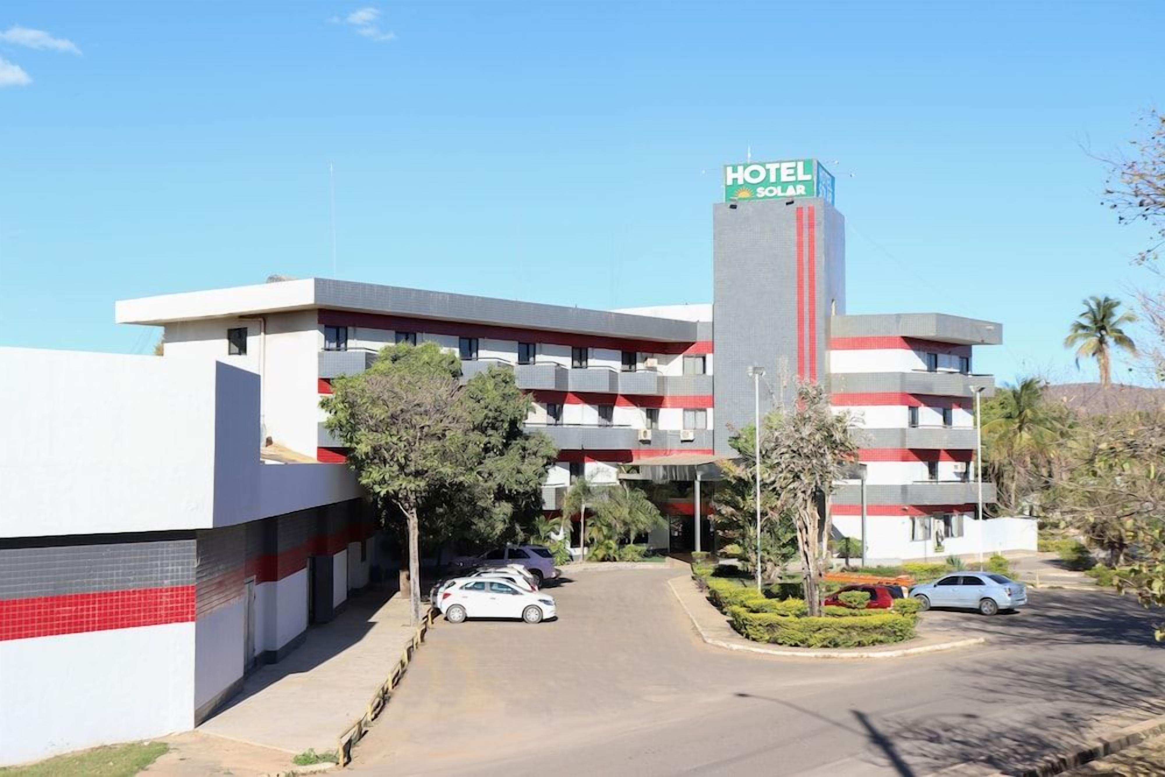 Hotel com placa grande, vários andares e área de estacionamento.