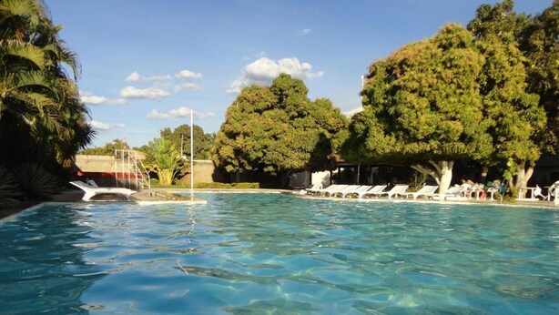 Uma piscina com água cristalina, rodeada por árvores e espreguiçadeiras.