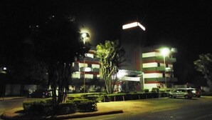 Um edifício com vários andares, estacionamento e postes de iluminação.