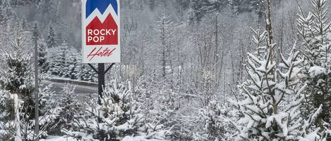 Placa do Rocky Pop Hotel cercada por árvores cobertas de neve.