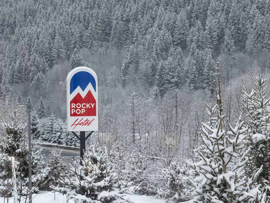 Placa do Rocky Pop Hotel cercada por árvores cobertas de neve.