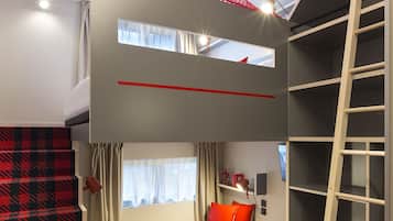 Quarto com beliche, um dossel vermelho em rede, escada e carpete estampado.
