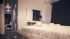 Quarto de hotel com uma cama grande, espelho, mesa de cabeceira e abajur.