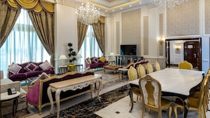 Uma sala de estar luxuosa, com um lustre grande, assentos confortáveis e uma televisão.