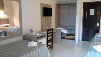 Quarto de hotel com duas camas, uma escrivaninha, uma cadeira, televisão e guarda-roupa.