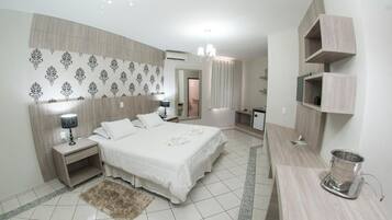 Quarto moderno com uma cama grande, mesas de cabeceira, escrivaninha e estantes embutidas.