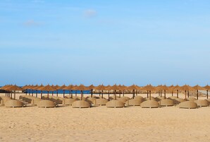 Na praia, espreguiçadeiras, guarda-sóis de praia, toalhas de praia 