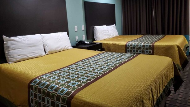 Duas camas de solteiro com cabeceiras, um telefone e uma janela com cortinas.