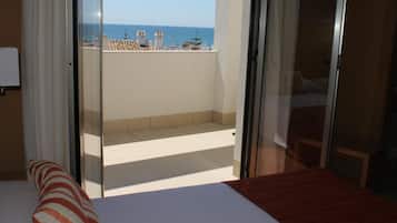 Quarto de hotel com cama, vista para o mar e varanda.