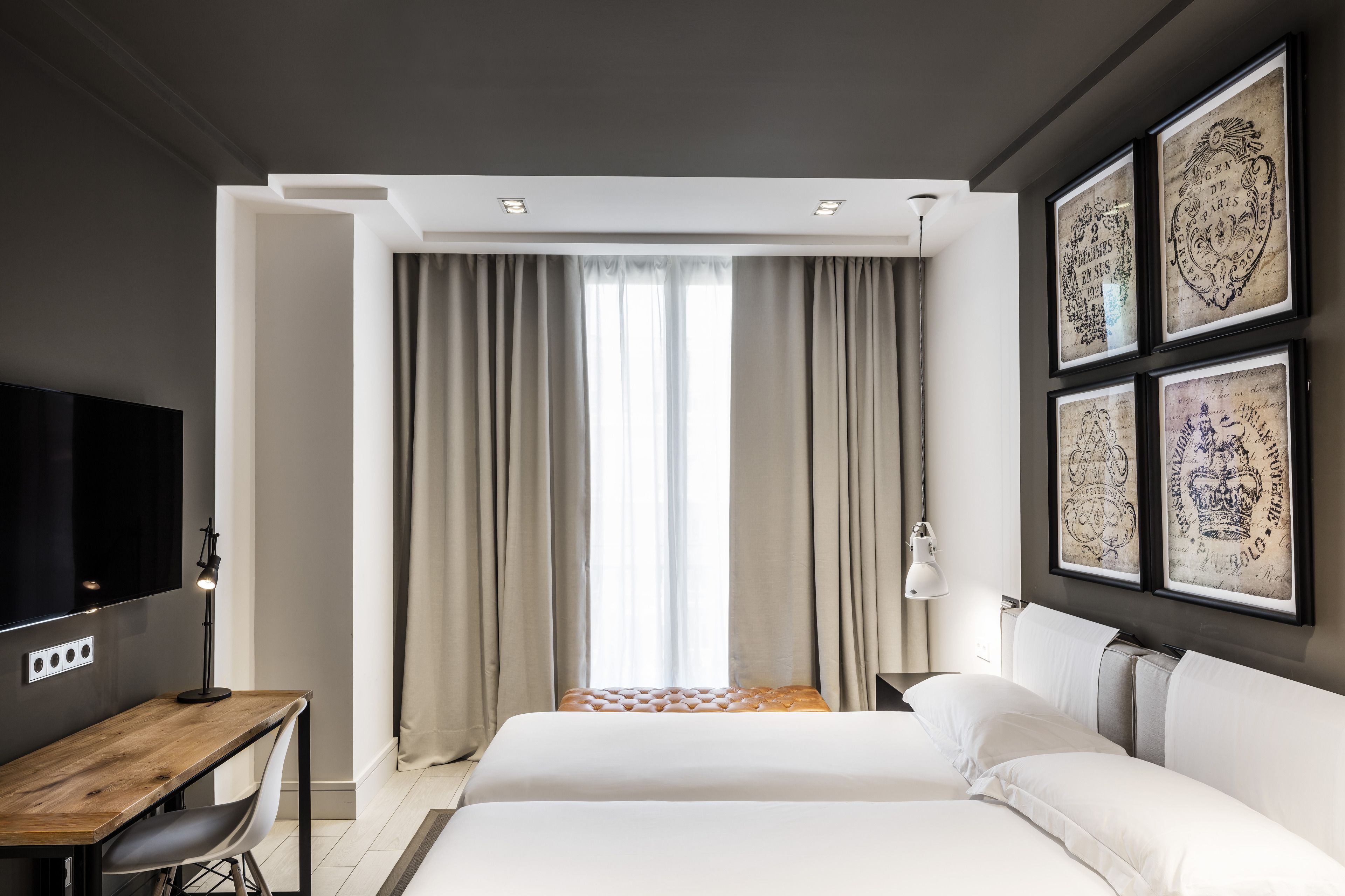Quarto de hotel moderno com uma cama grande, uma escrivaninha e uma televisão.
