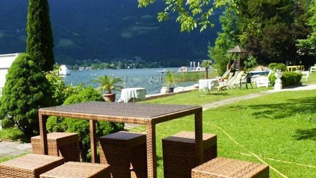 Uma área de estar ao ar livre com cestaria e vista para um lago e montanhas.