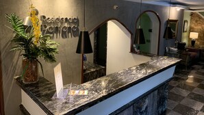 Uma receção com bancada de mármore, uma planta em vaso e uma placa com a inscrição "Residencial Portales".