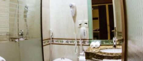 Casa de banho com sanita, lavatório e chuveiro.