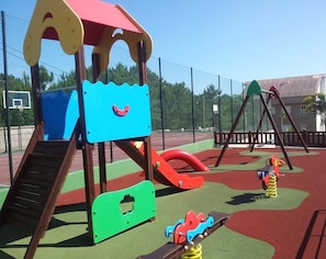Um parquinho com estrutura de escalada, escorregadores e balanços.
