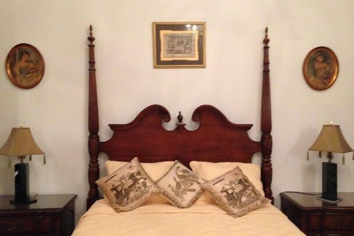Uma cama com cabeceira de madeira, duas mesas de cabeceira e um quadro na parede.