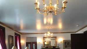 Um quarto com lustre, lareira, sofá, mesa e cama.