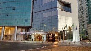 Um hotel moderno com fachada curva de vidro e um letreiro chamativo com a palavra 'Windsor' na lateral.