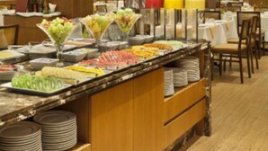 Um buffet com diversos alimentos e bebidas, painéis de madeira e design de interiores moderno.