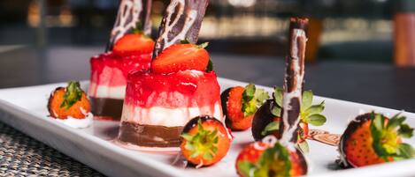 Uma bandeja de sobremesas com bolos em camadas, morangos e decorações de chocolate.