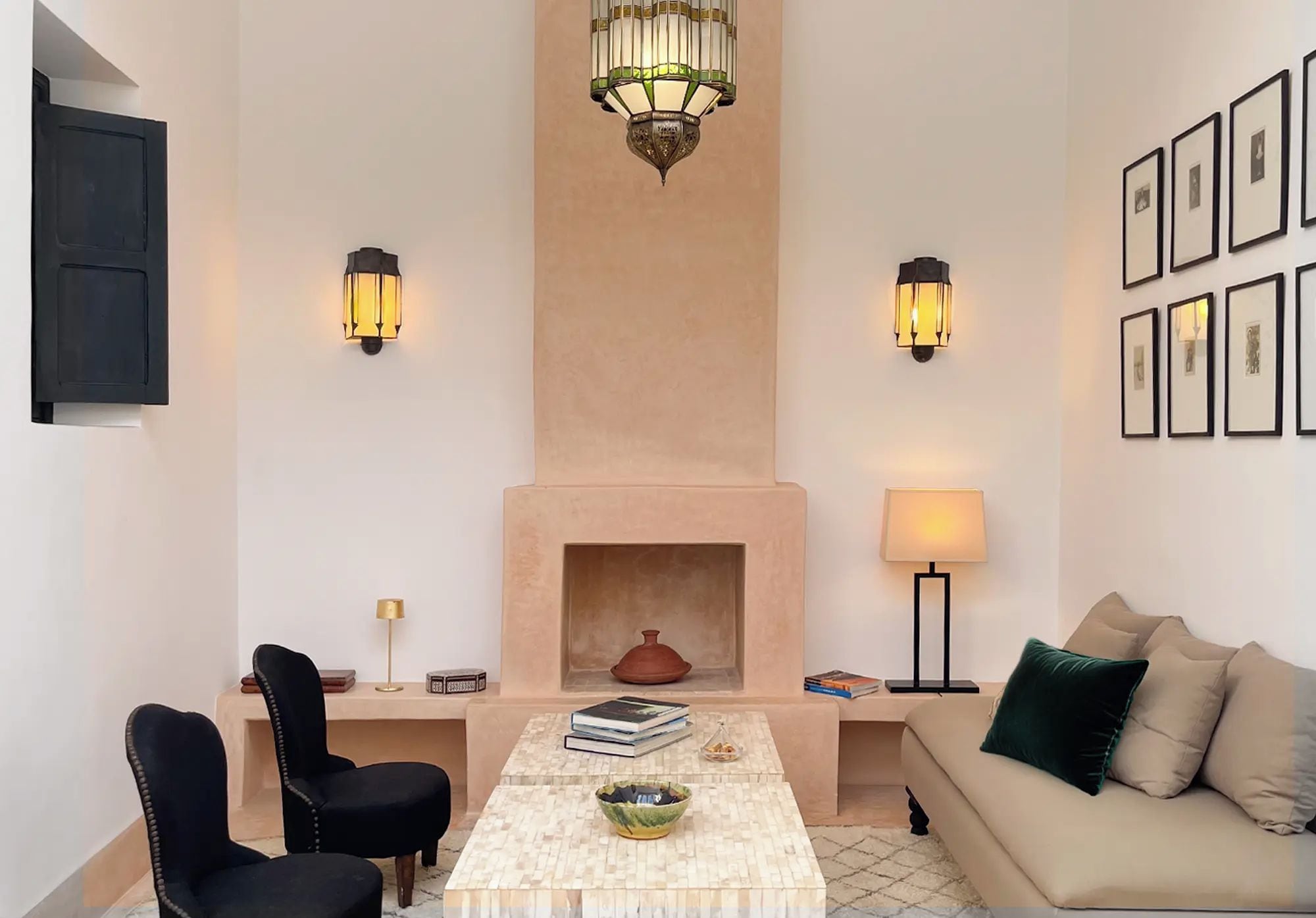 Uma sala de estar com lareira, duas luminárias de parede, um sofá, uma mesa de centro e uma estante.