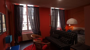 Quarto com sofá, cadeira, mesa, abajur e radiador.