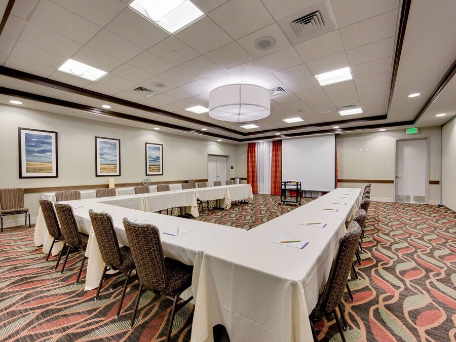 Uma sala de conferências com uma mesa comprida, cadeiras e quadros nas paredes.