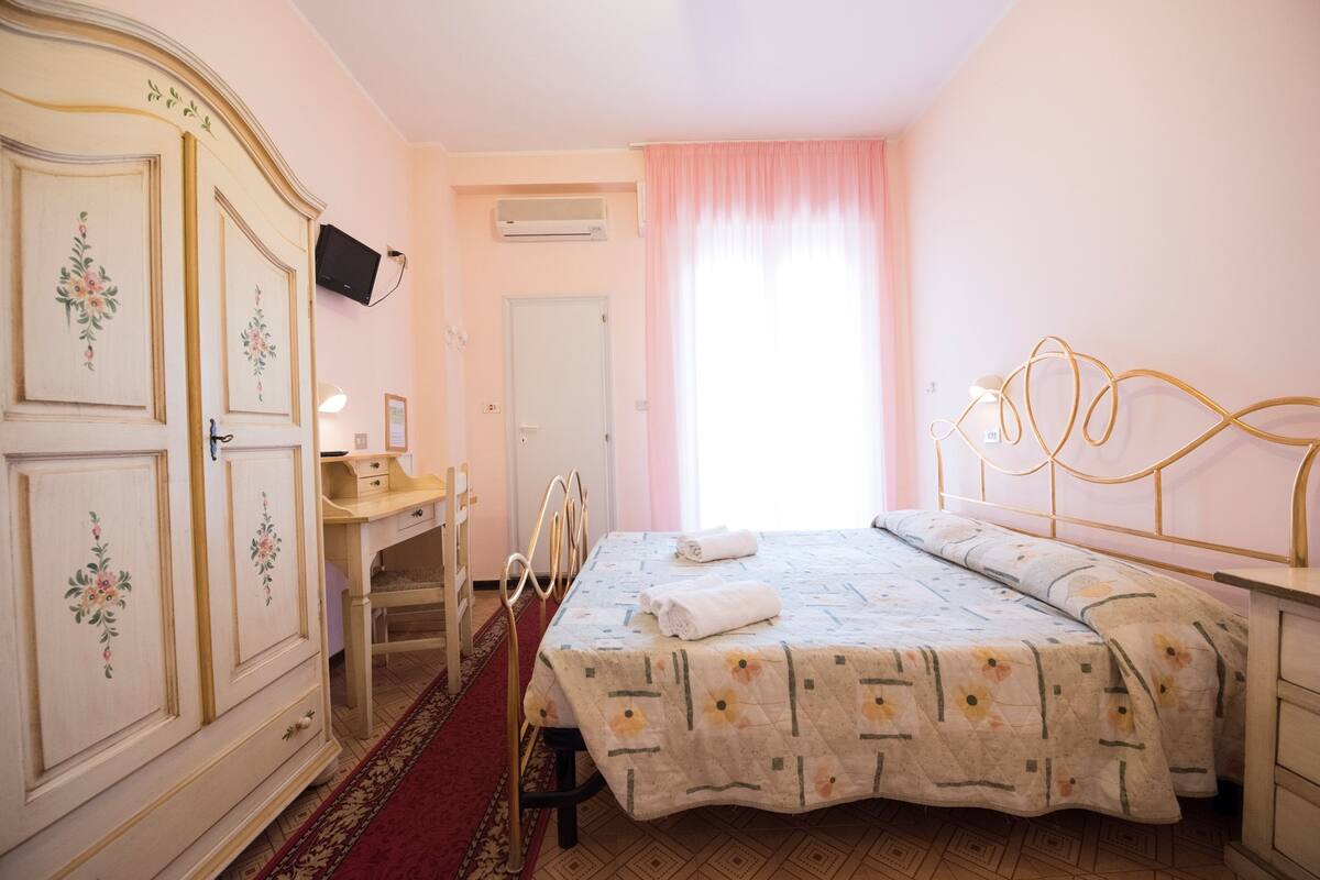 Um quarto com uma cama, uma escrivaninha e um guarda-roupa.