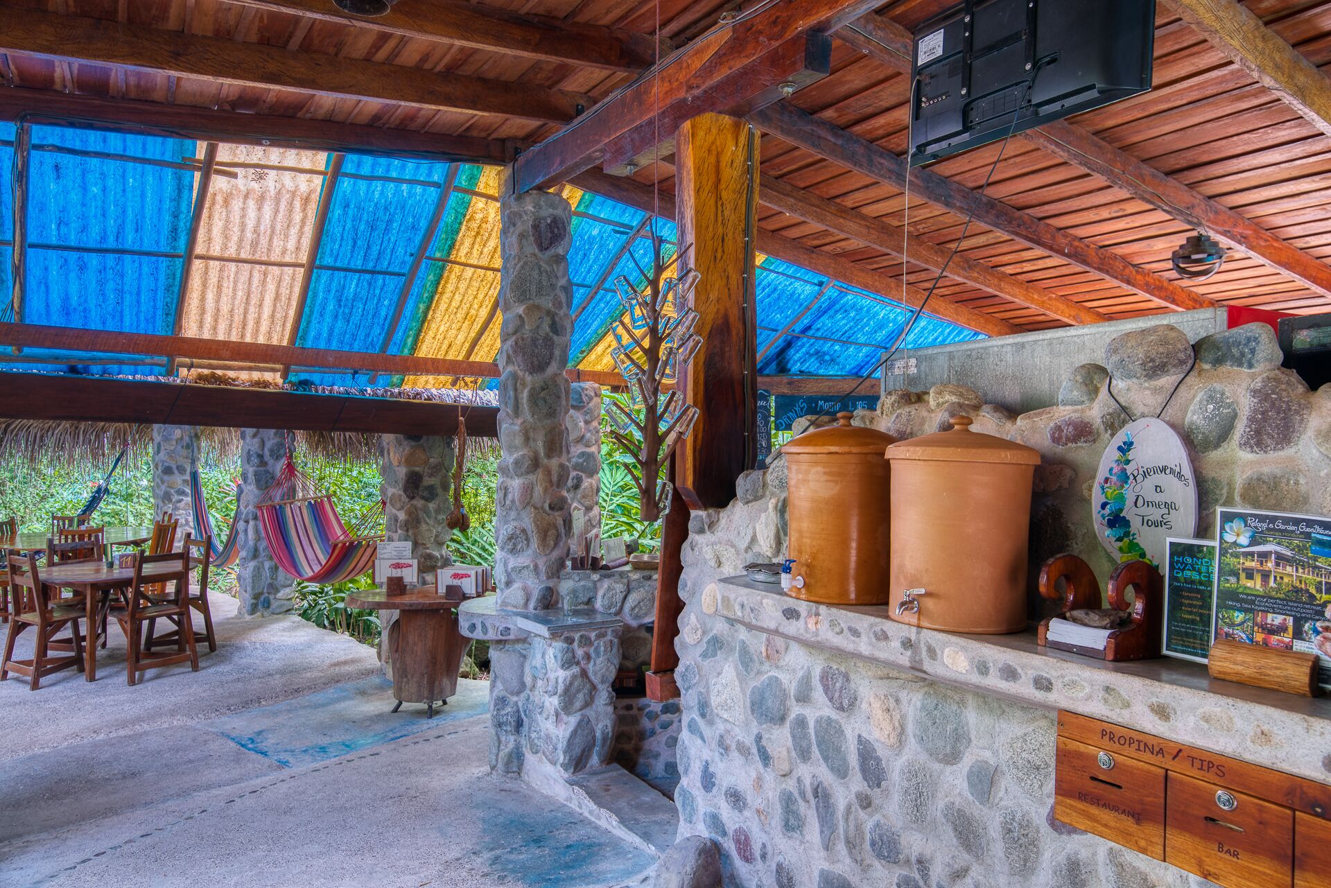 Um restaurante rústico com paredes de pedra, móveis de madeira e um telhado de palha.