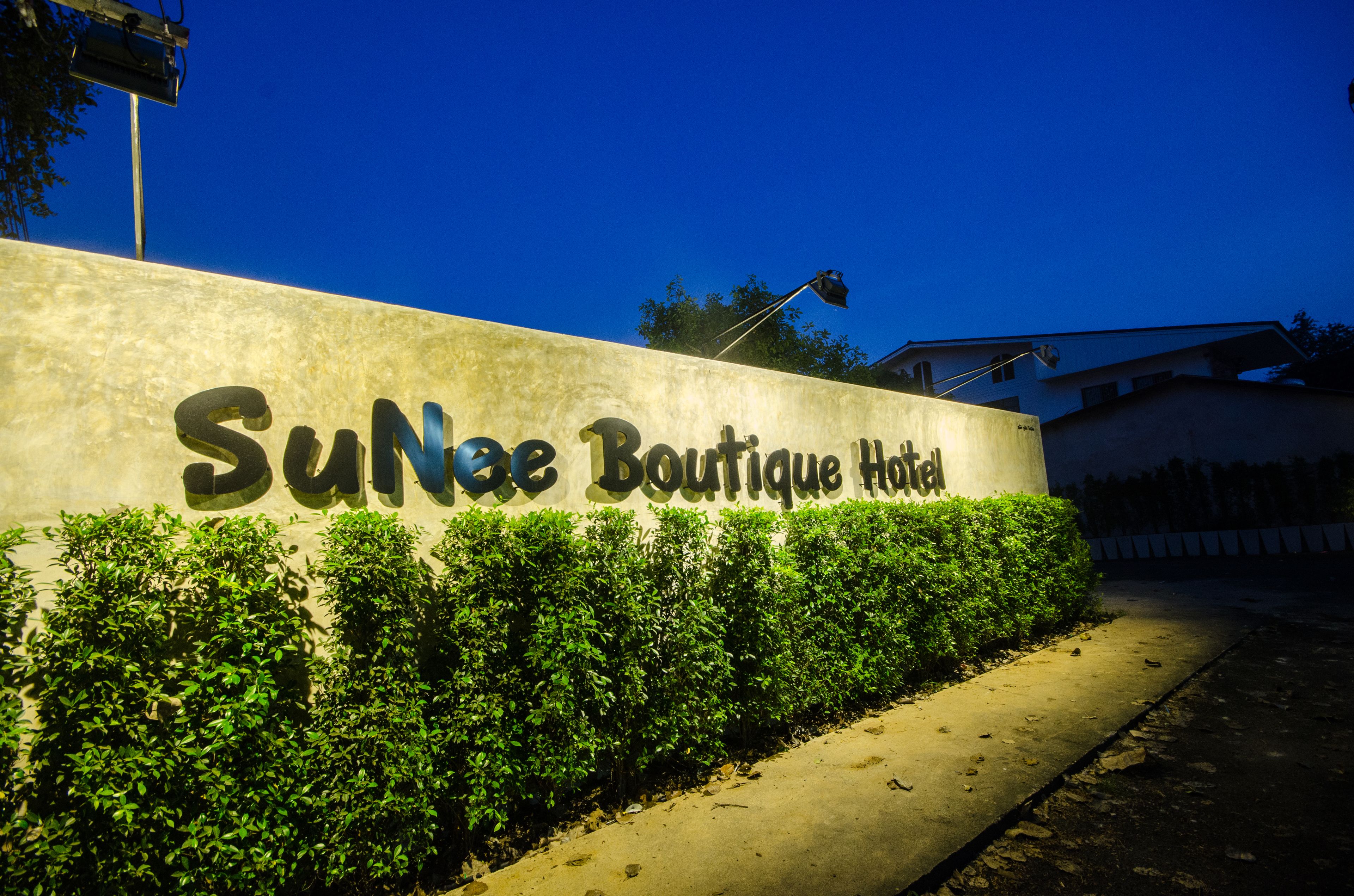 Placa indicando o Sunae Boutique Hotel, com a fachada do hotel bem visível.